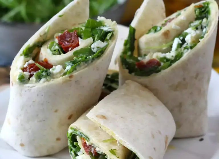 Mediterranean wrap stuffed with hummus, arugula, peppers and feta