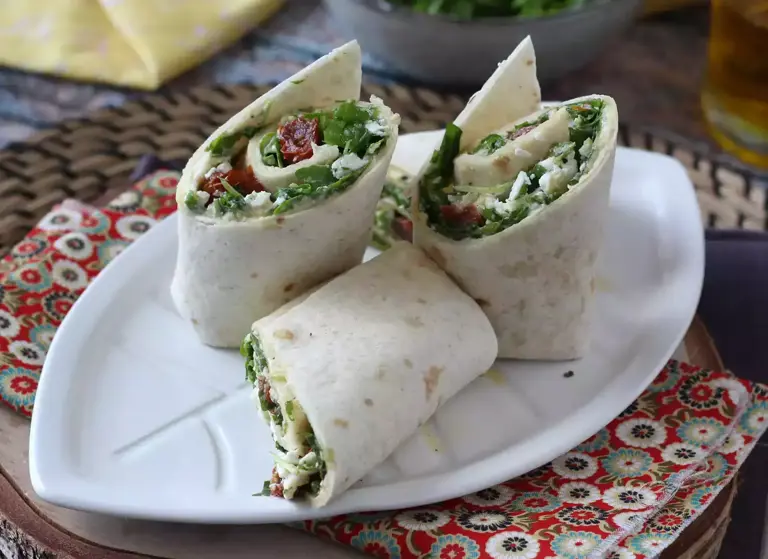 Mediterranean wrap stuffed with hummus, arugula, peppers and feta