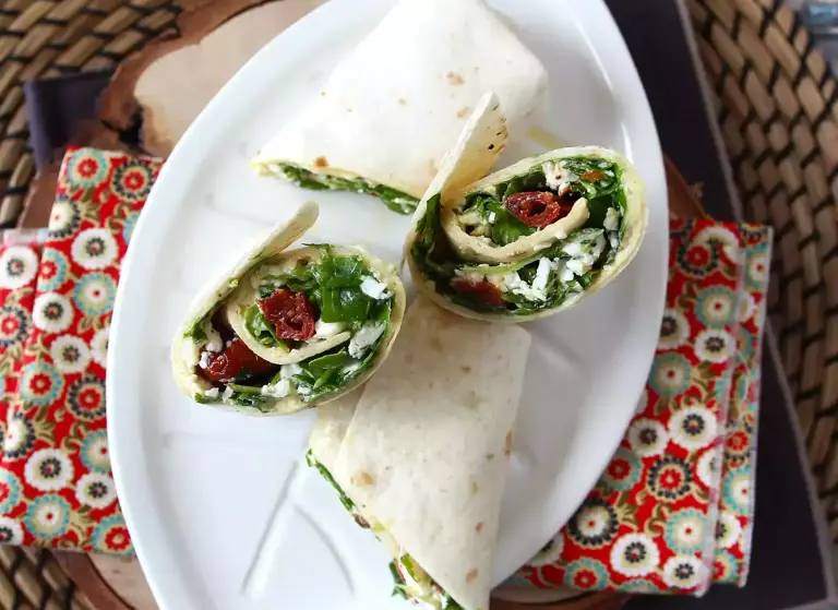 Mediterranean wrap stuffed with hummus, arugula, peppers and feta