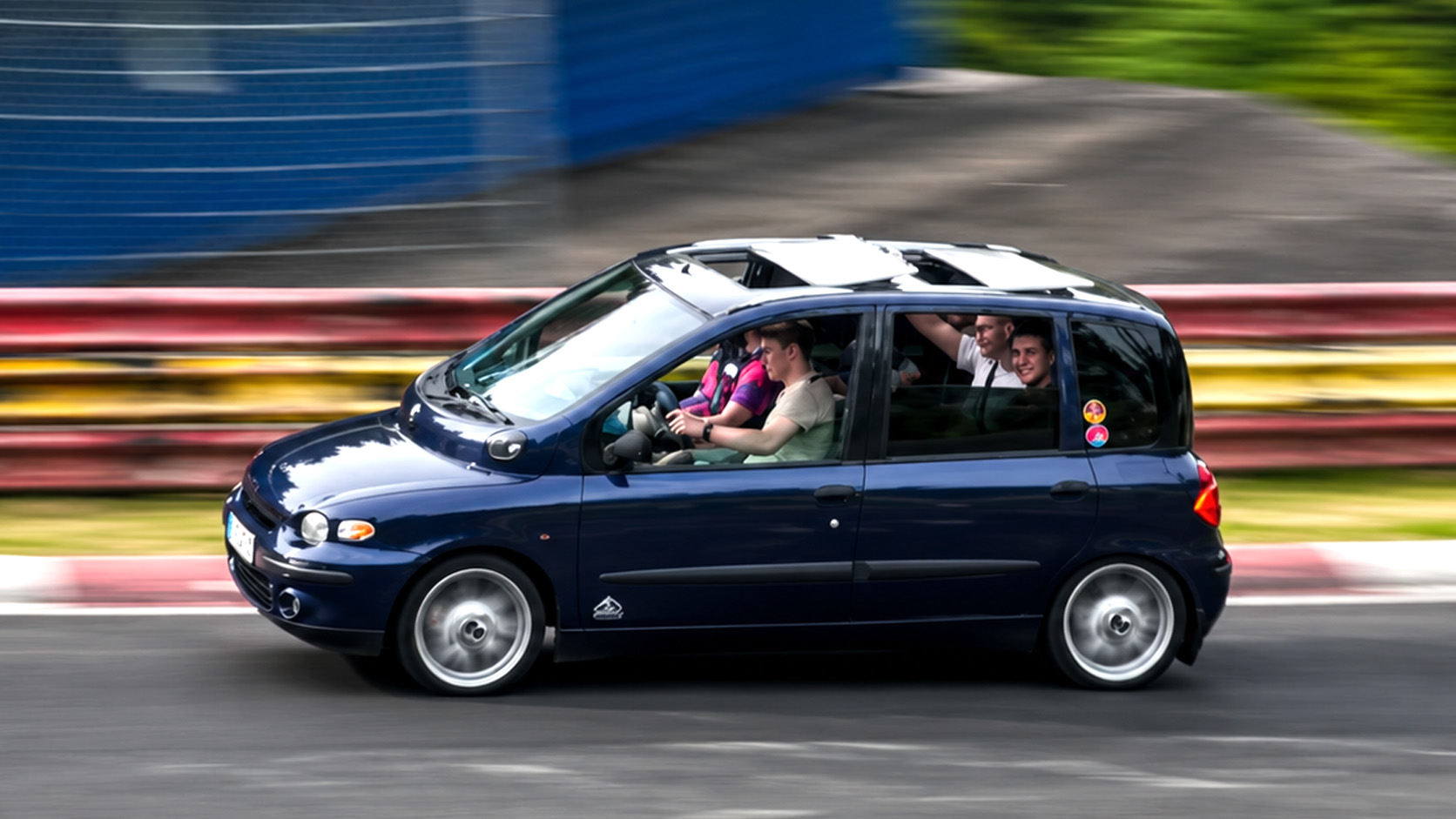 Vollbesetztes langsames Auto nimmt eine Kurve auf dem Nürburgring zu ...