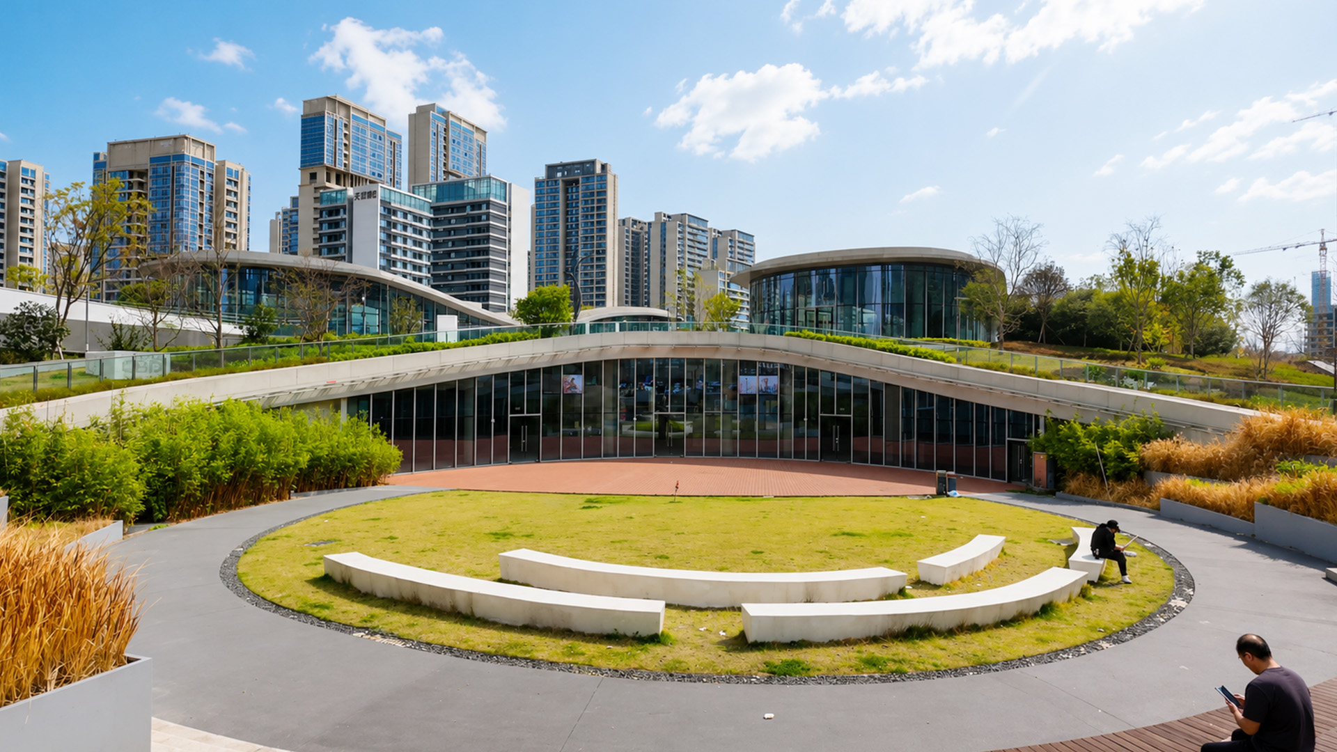 A spacious green plaza with buildings blending into nature