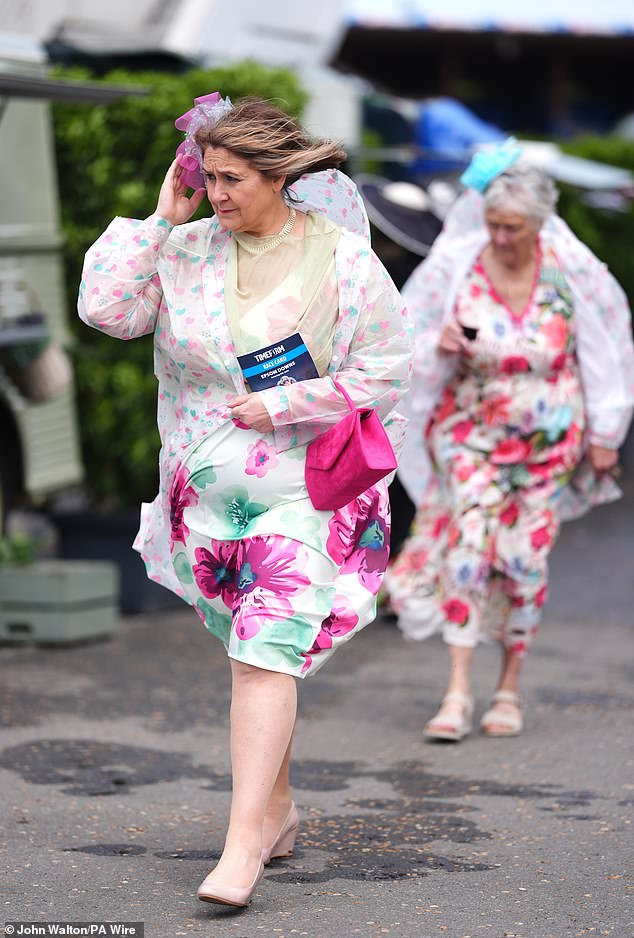 Epsom revellers shelter from the rain and wind as the clouds roll in on ...