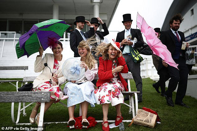 Epsom revellers shelter from the rain and wind as the clouds roll in on ...