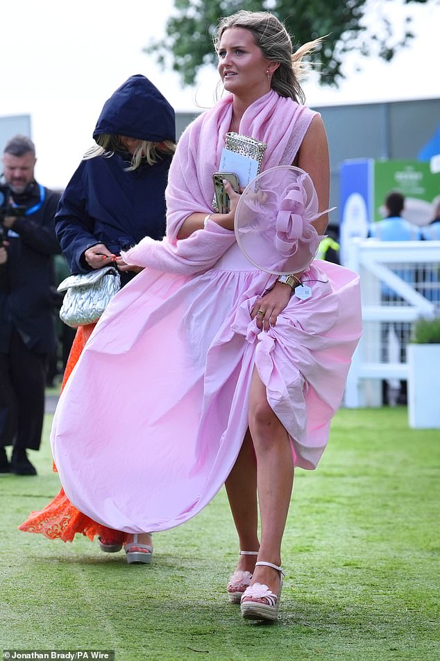 Epsom revellers shelter from the rain and wind as the clouds roll in on ...