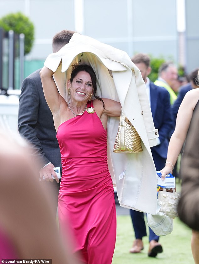 Epsom revellers shelter from the rain and wind as the clouds roll in on ...