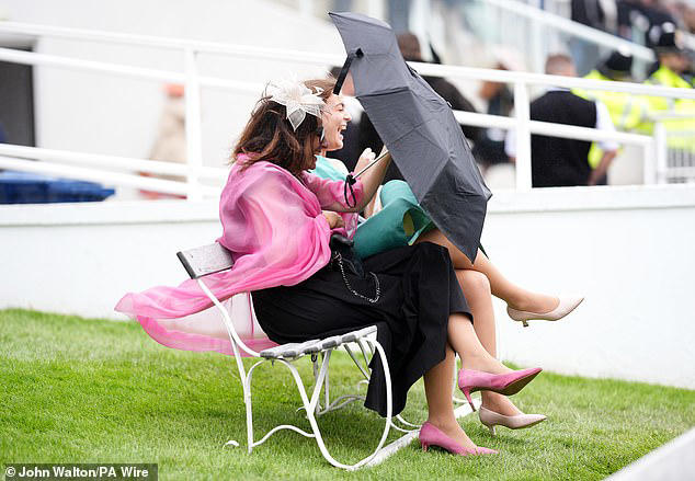 Epsom revellers shelter from the rain and wind as the clouds roll in on ...