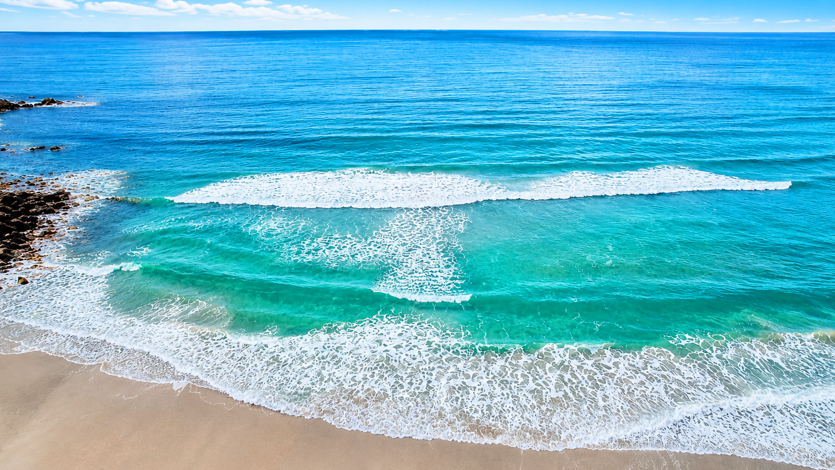 Endless ocean waves rolling across a quiet shoreline