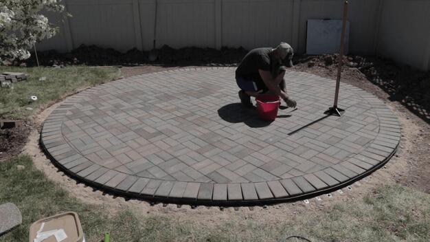 Guy builds DIY round paver patio in backyard