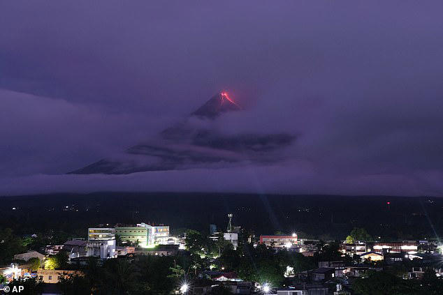 Incredible moment a meteor streaks through the sky over an erupting ...