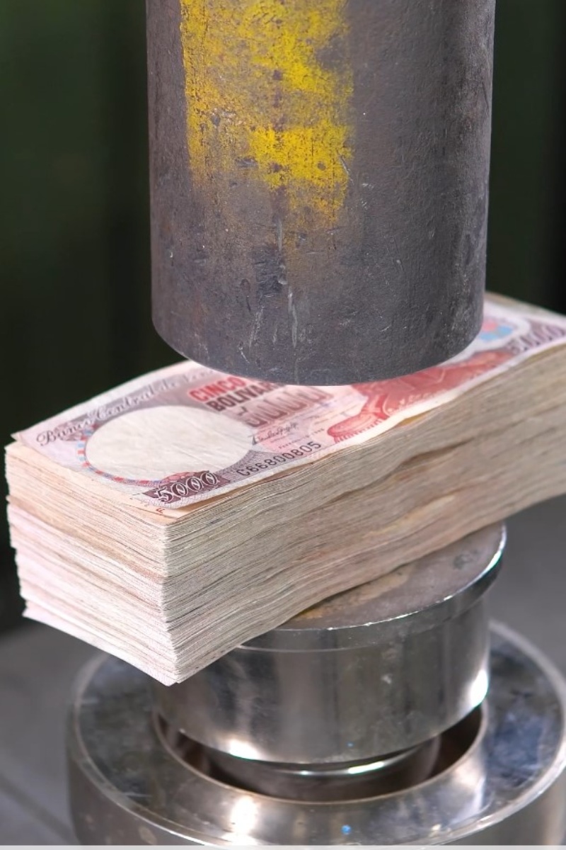 Crushing money under hydraulic press