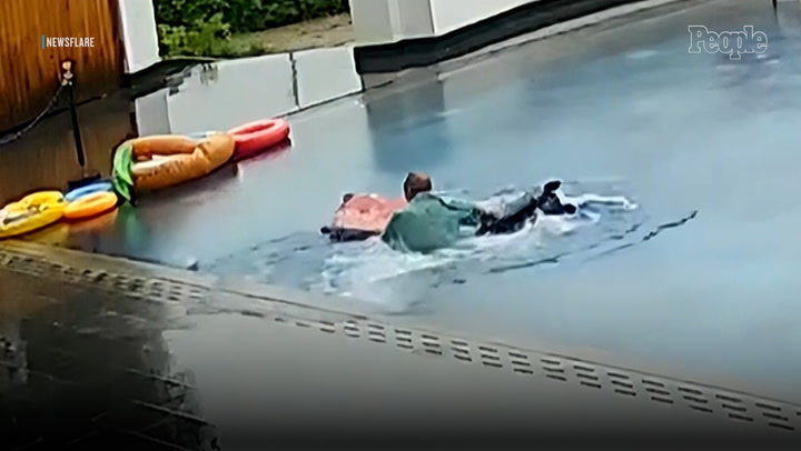 Hotel porter walks into swimming pool while carrying guests’ baggage in ...