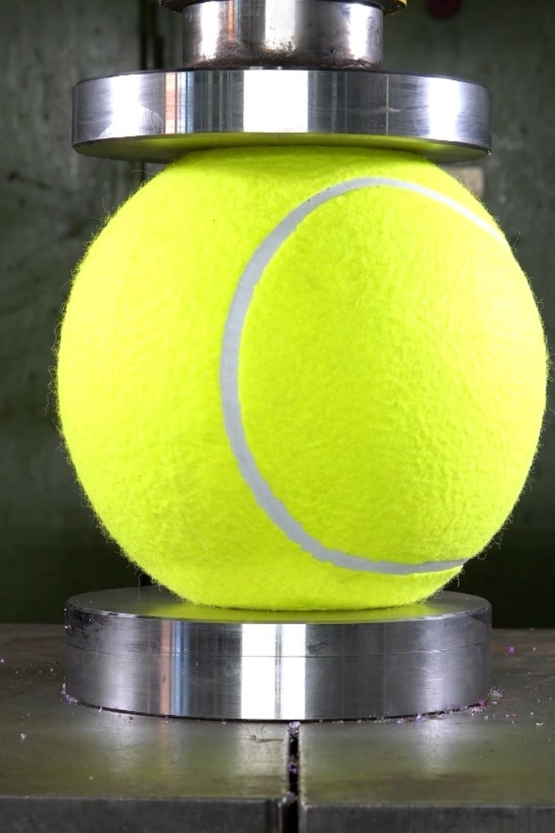 Crushing a tennis ball under hydraulic press