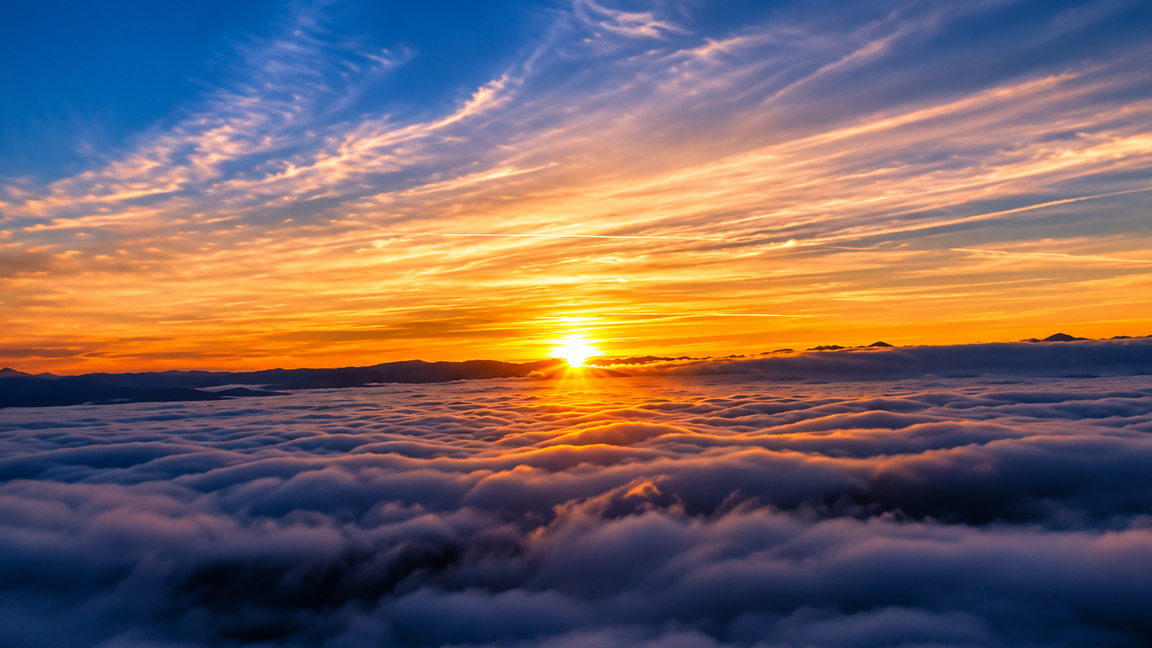 The sunrise hidden above an endless ocean of clouds