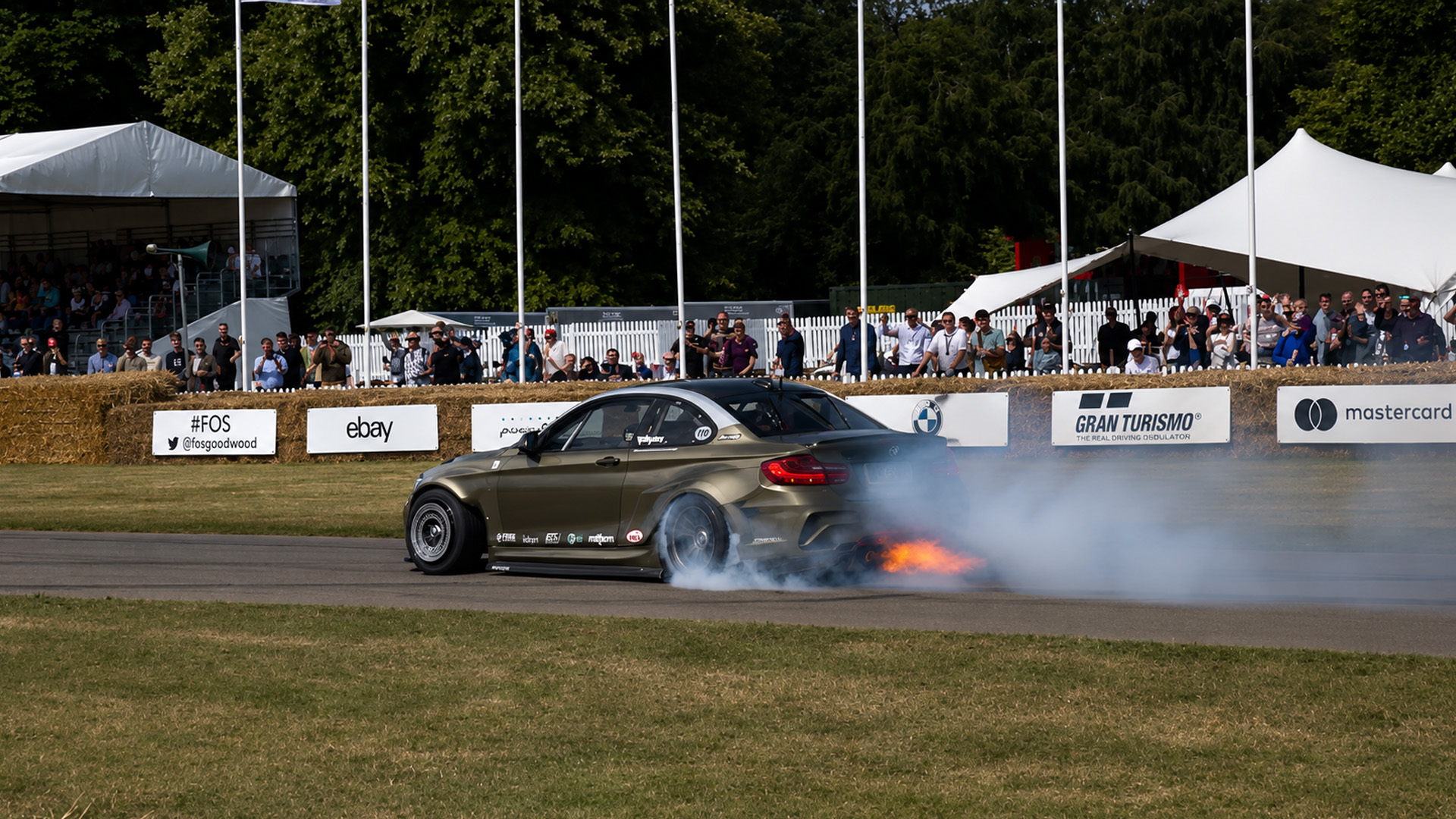 Crowd watches a fiery BMW slide on race track