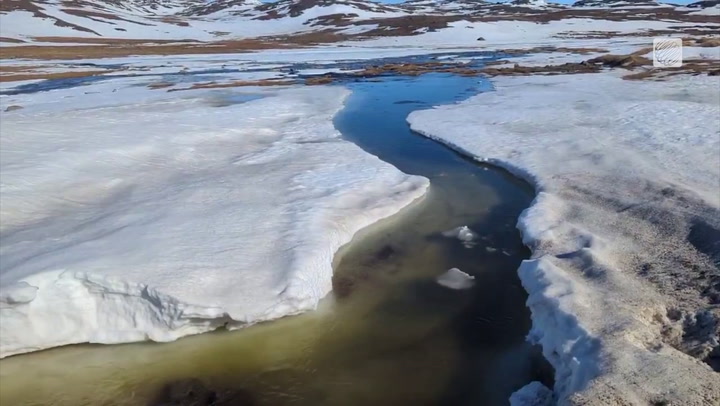 Meltwater stream carves a path through the frozen tundra