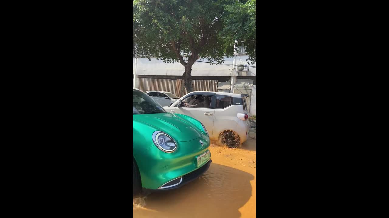 Mini EV pushes through muddy floodwater after water pipe burst in ...