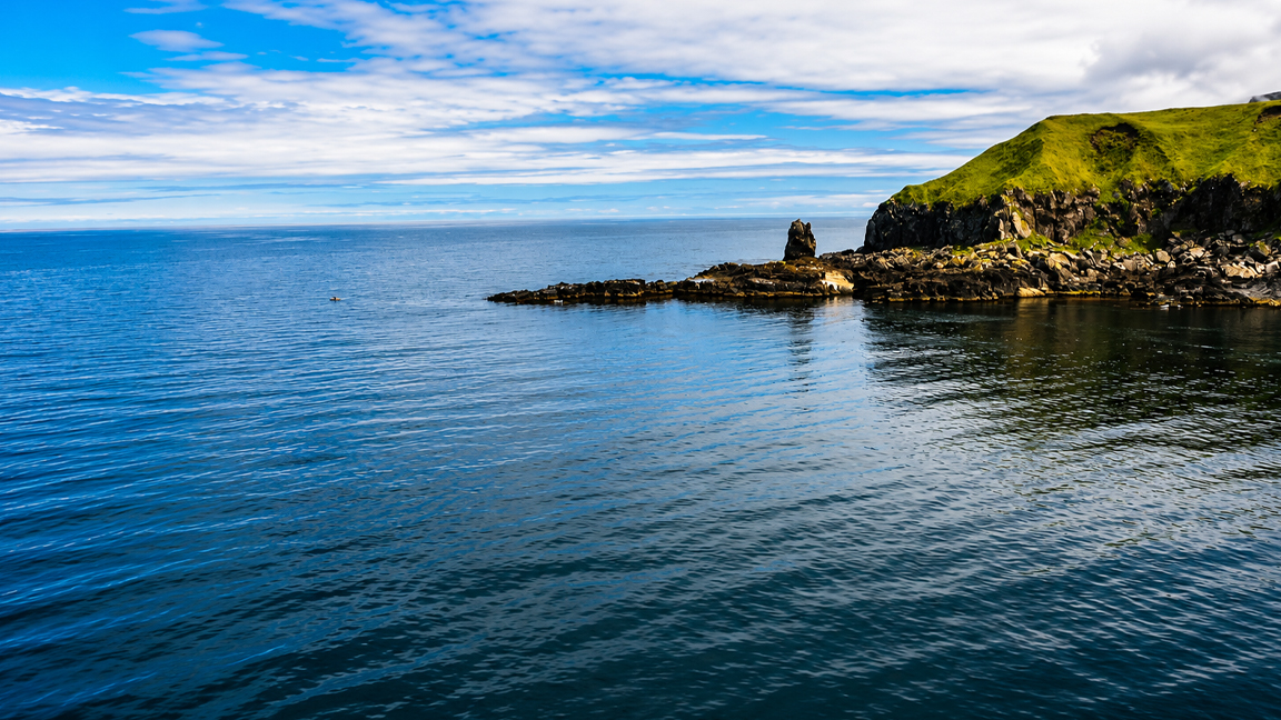 Peaceful coastal headland and calm ocean waters under a blue sky