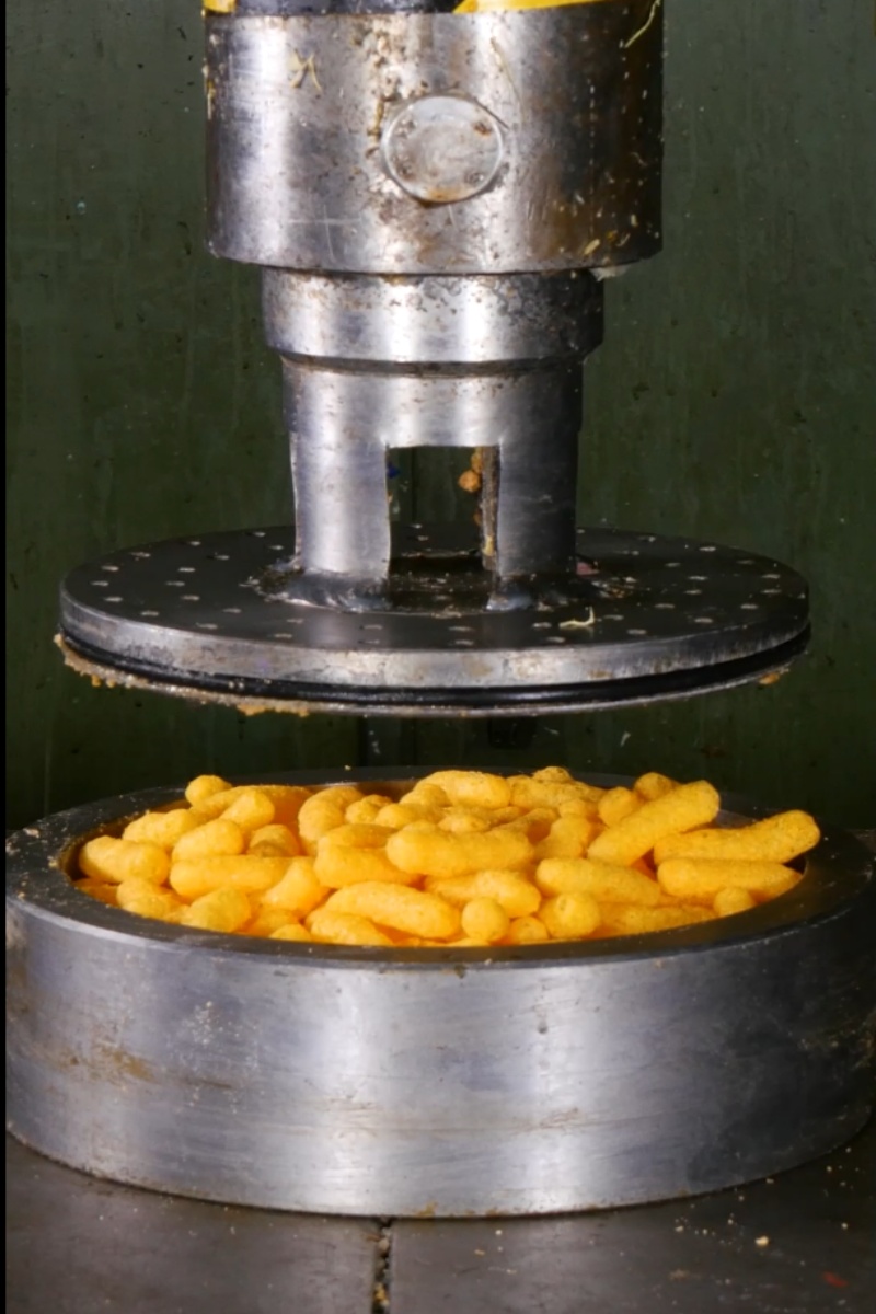 Hydraulic press crushing cheese snacks