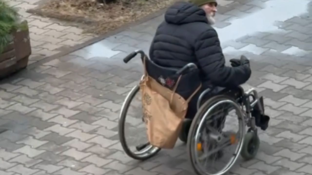 Man propels his wheelchair like a foot-powered scooter