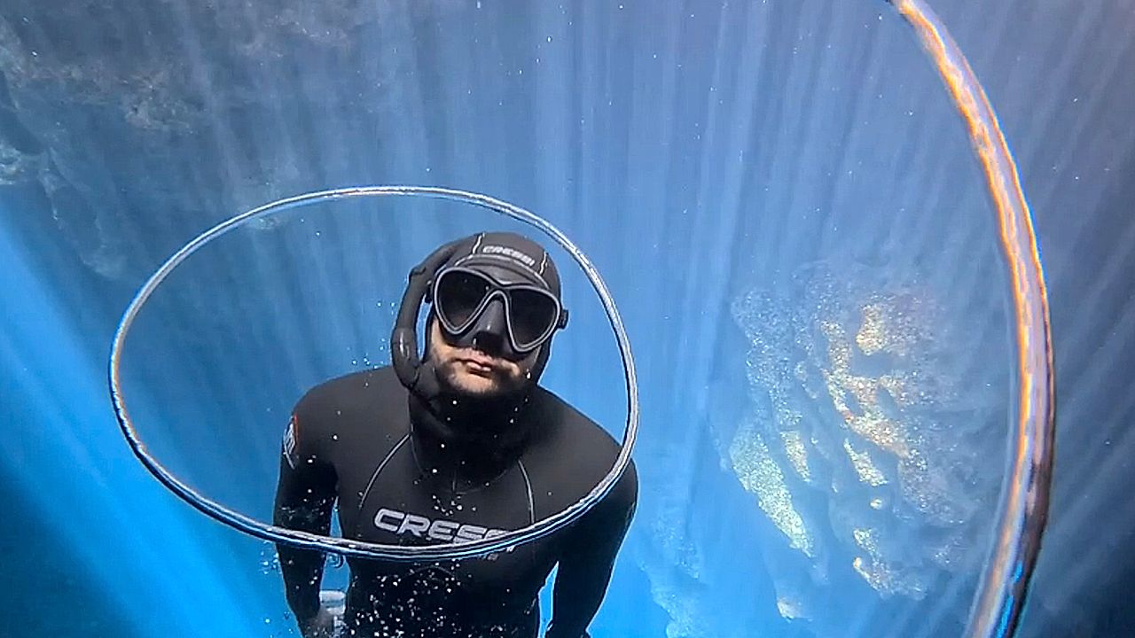 Serene moment freediver swims through bubble rings in sea cave off Spain
