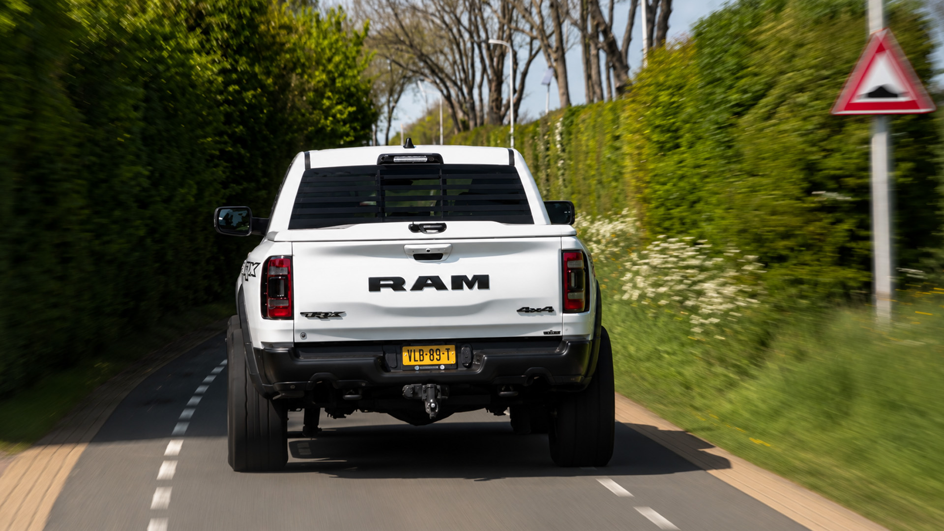 Dodge RAM 1500 accelerates hard on a narrow road