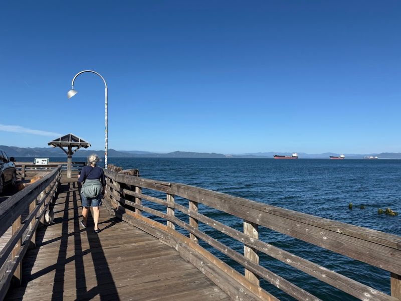 A scenic waterfront park in Oregon with a wooden viewing pier, passing ...