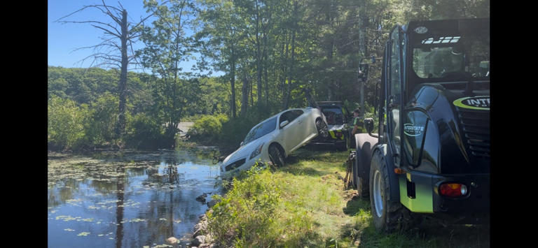 First responders pull car partially submerged in pond