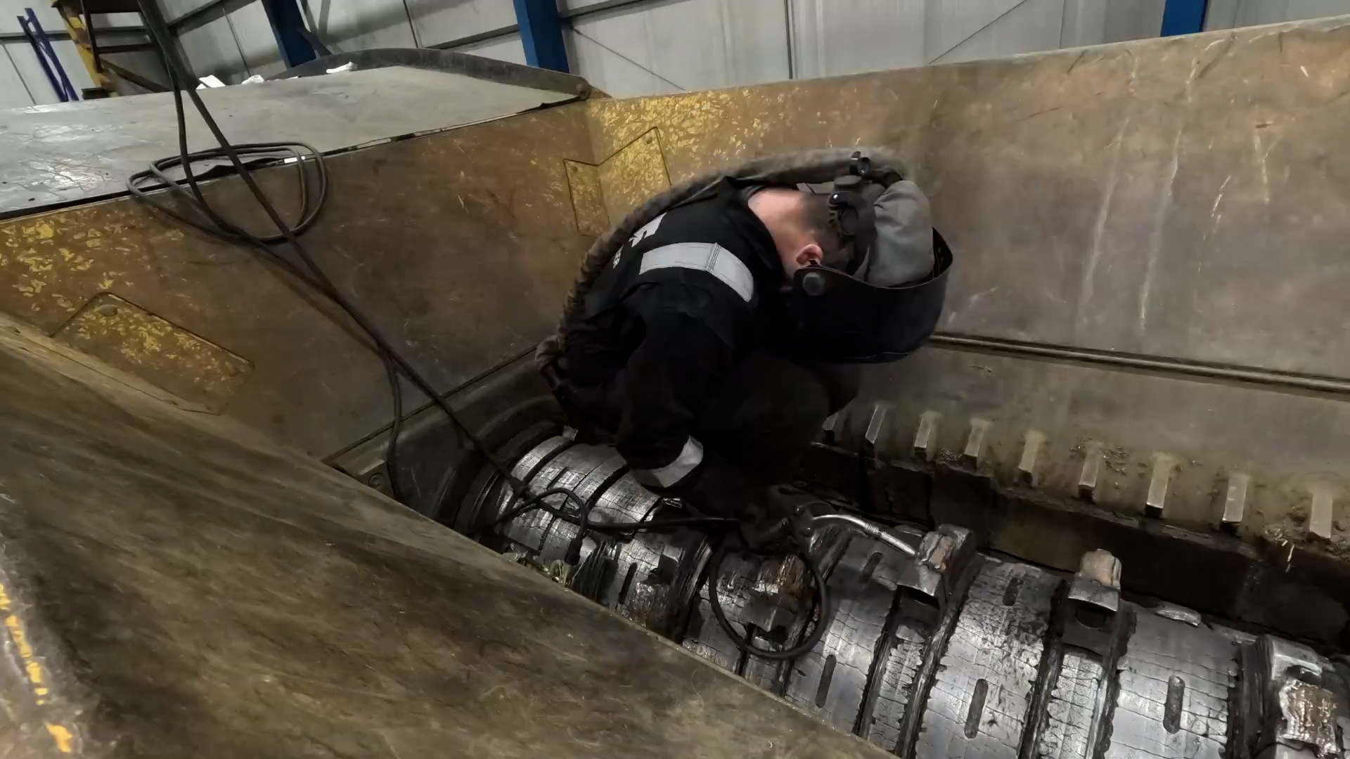 Technician performing industrial shredder maintenance inside heavy ...
