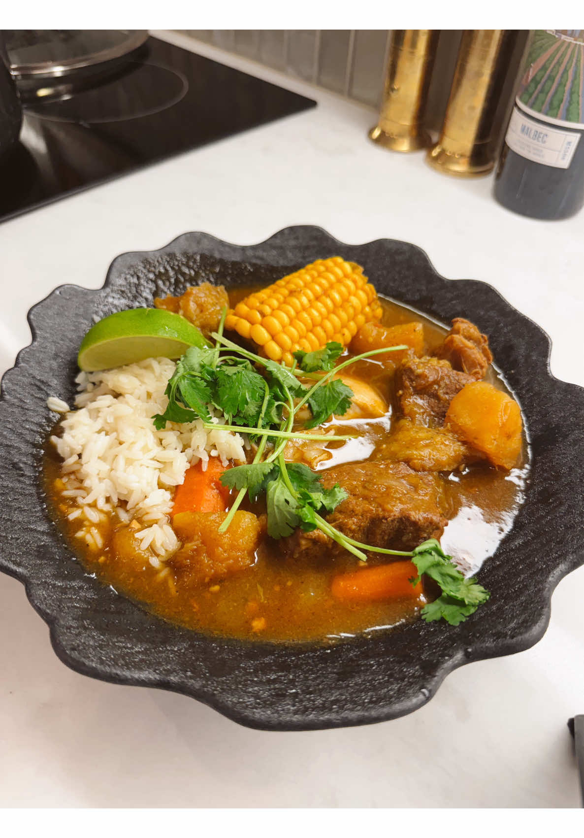 A rich beef and vegetable stew with corn on the cob, rice, and a fresh ...
