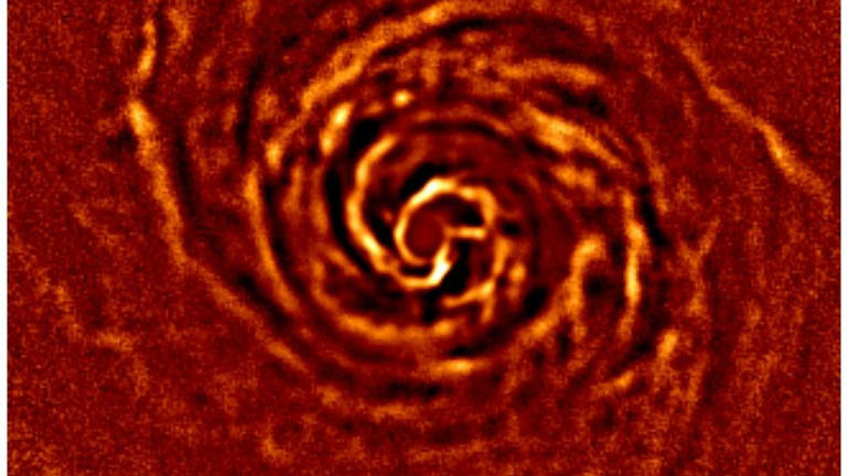 Distortions in young planet-forming disc suggests hidden gas giants