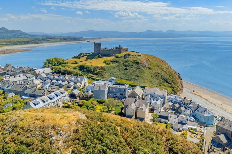 Between the sea on one side and a castle on the other is a house with ...