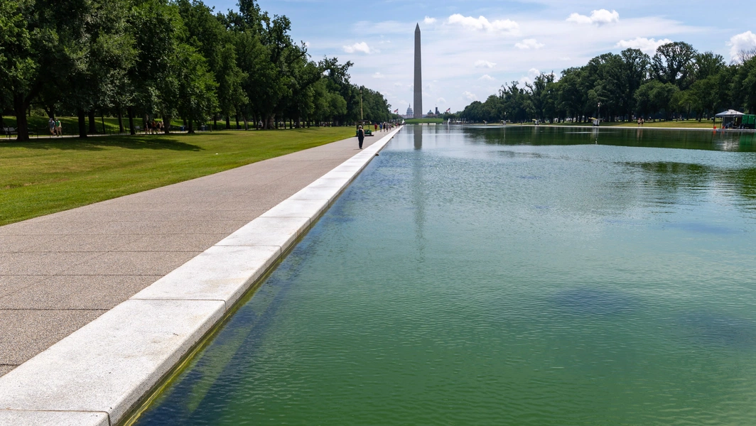 Workers pour hydrogen peroxide into green reflecting pool
