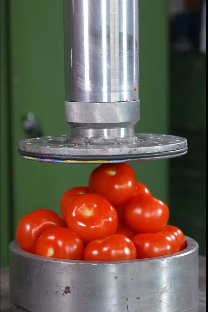 Hydraulic press crushing tomatoes