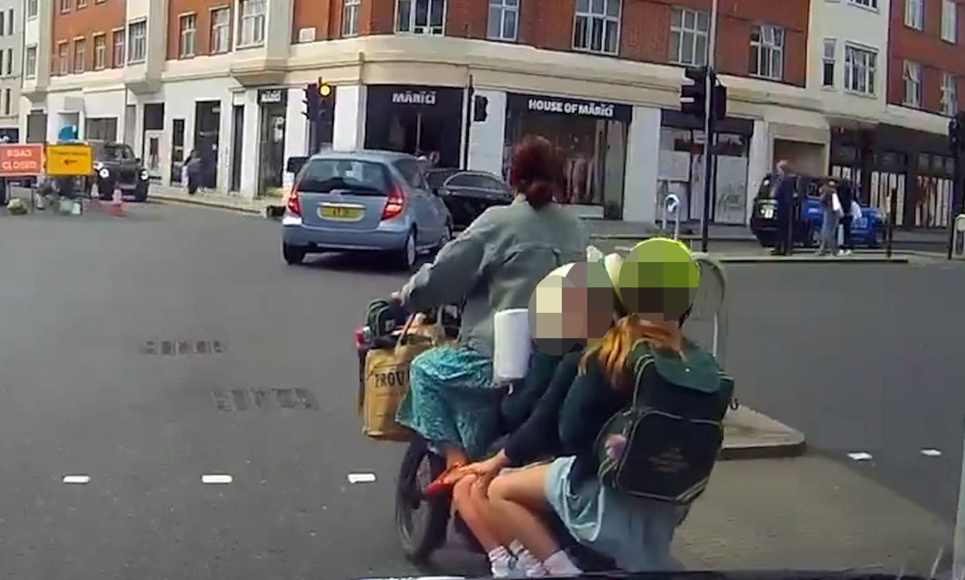Moment woman cyclist with three children riding on back pedals through ...