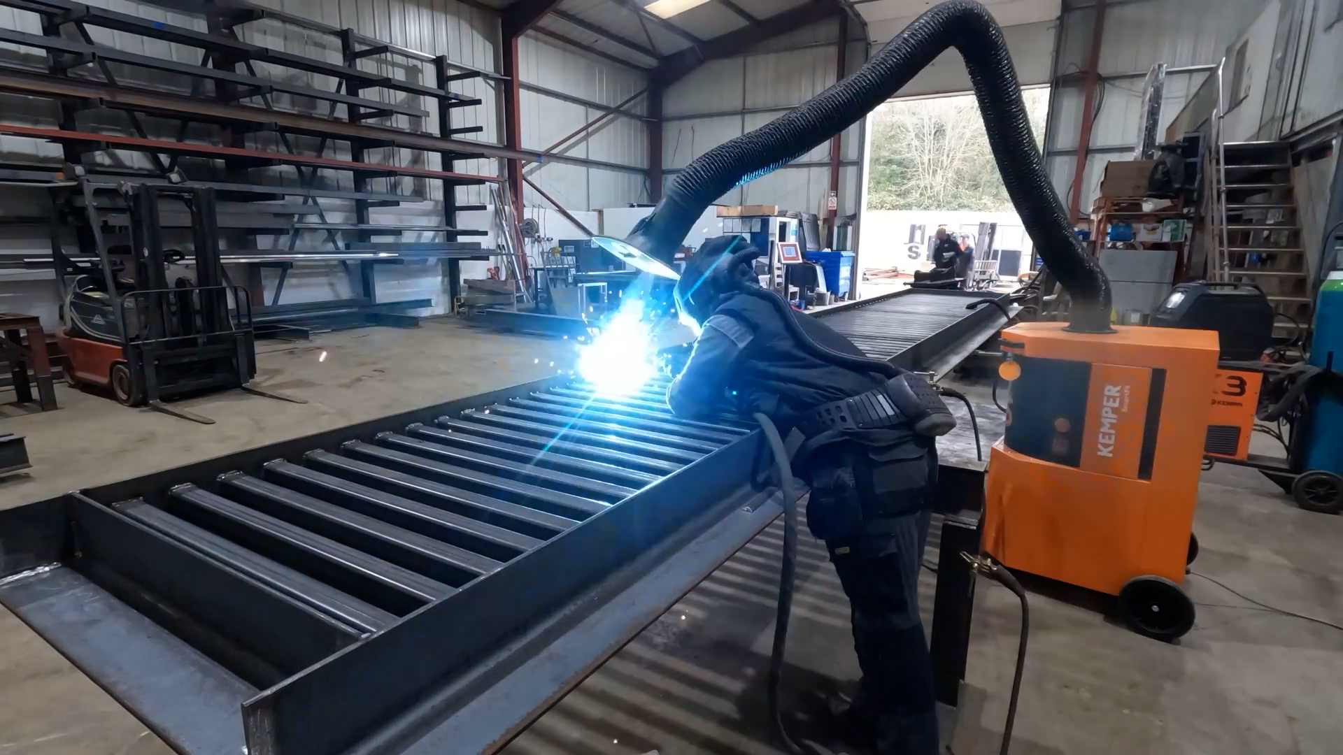 Welder fabricating heavy-duty screening deck with fume extraction system