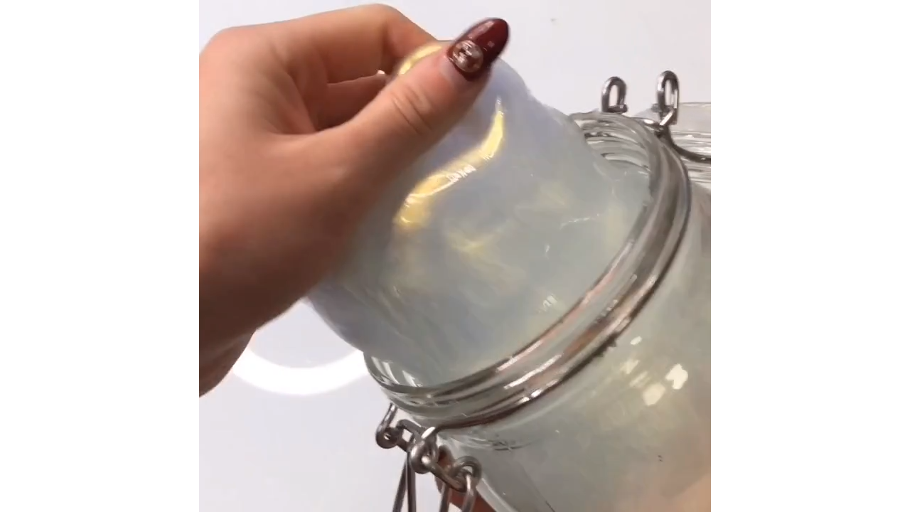 Stretching and pulling crystal clear slime from glass jar creating ...