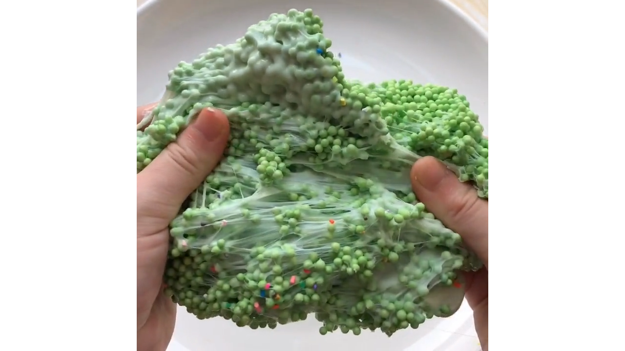 Stretching and squeezing mint green foam bead slime creating crunchy ...