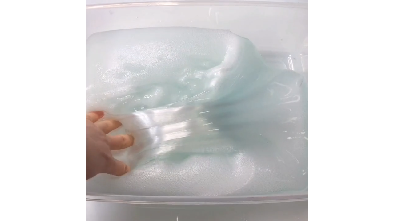 Stretching and pressing pearl blue glossy slime creating smooth crystal ...