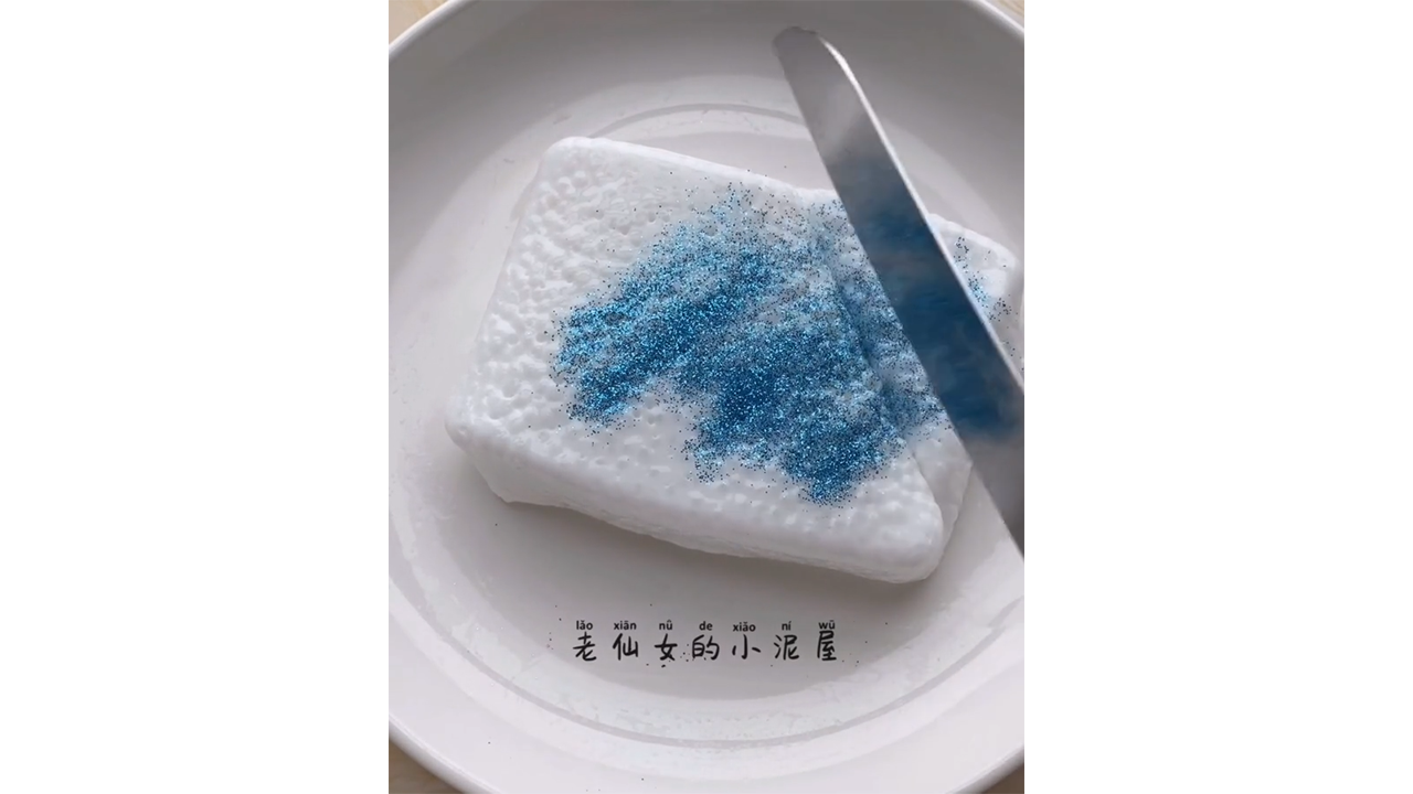 Slicing white foam slime with blue glitter creating crunchy snowy crumbles