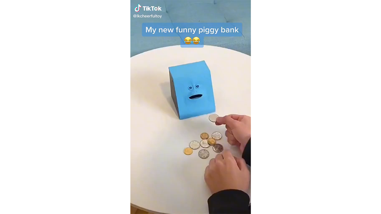 Feeding coins to a funny blue piggy bank with a surprising reaction