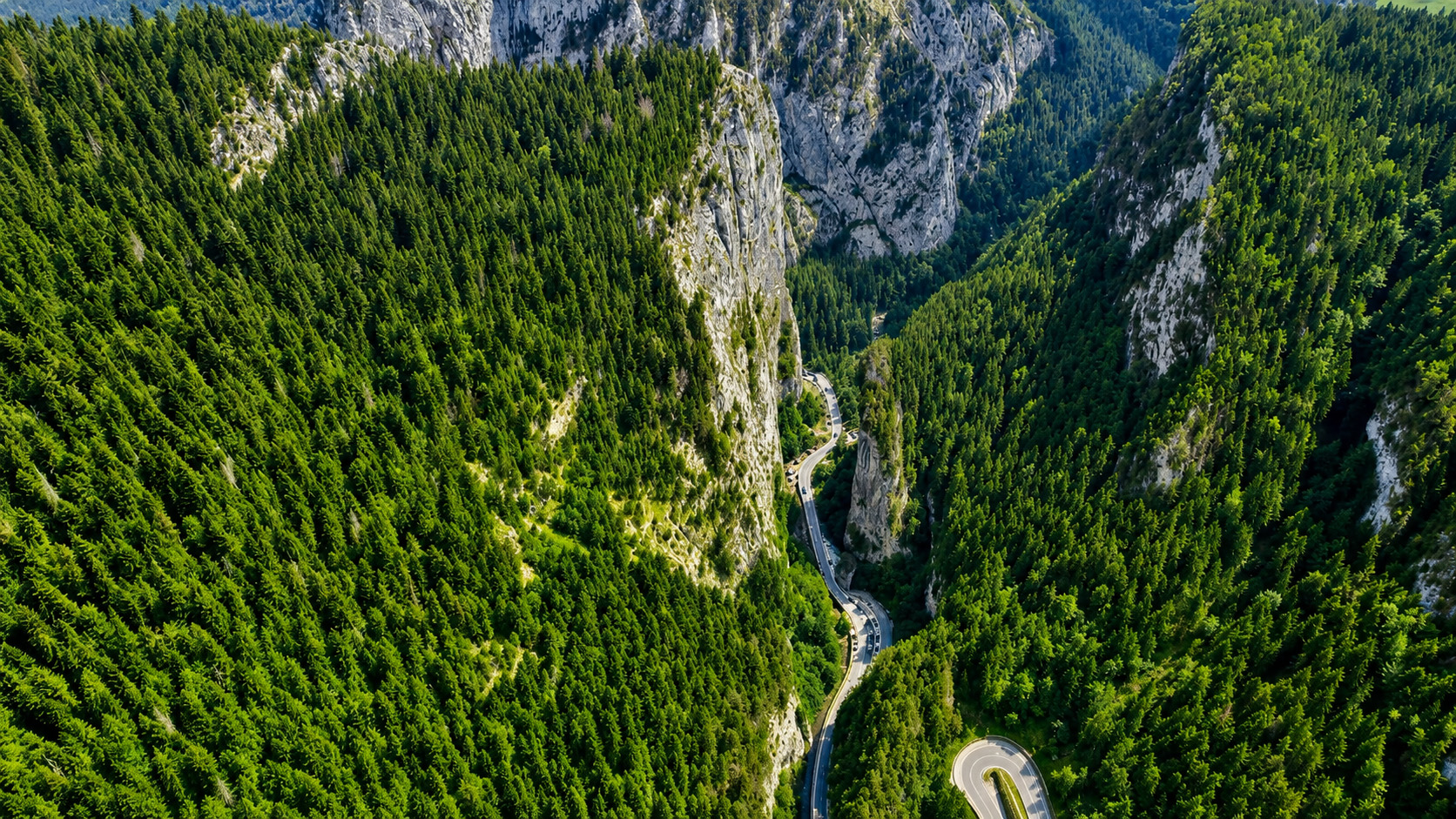 A narrow Romanian road cutting through towering limestone cliffs