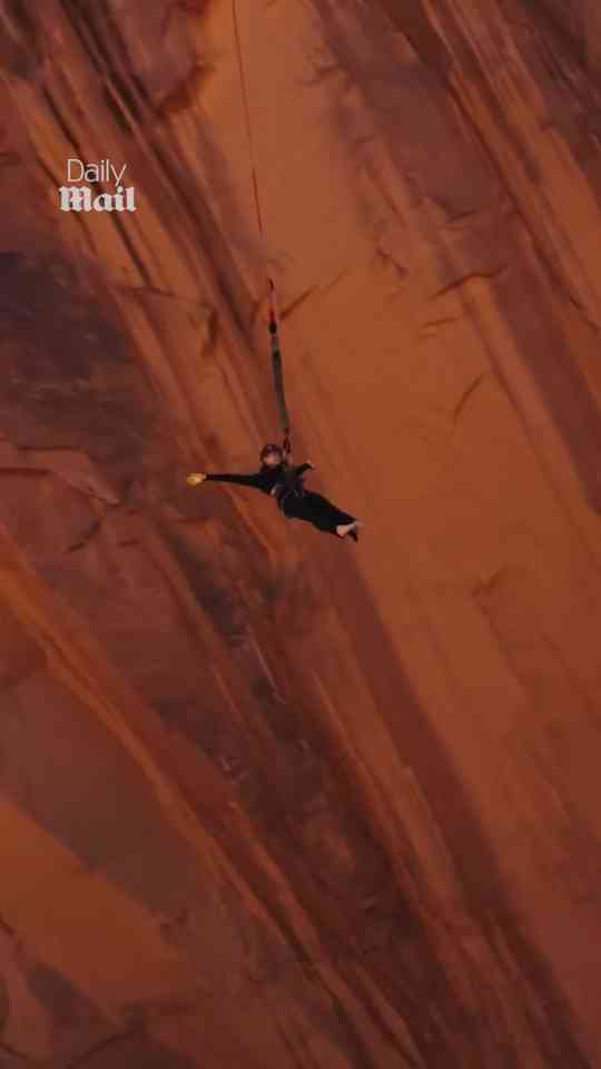 Thrill-seeker swings from cliff in daring stunt
