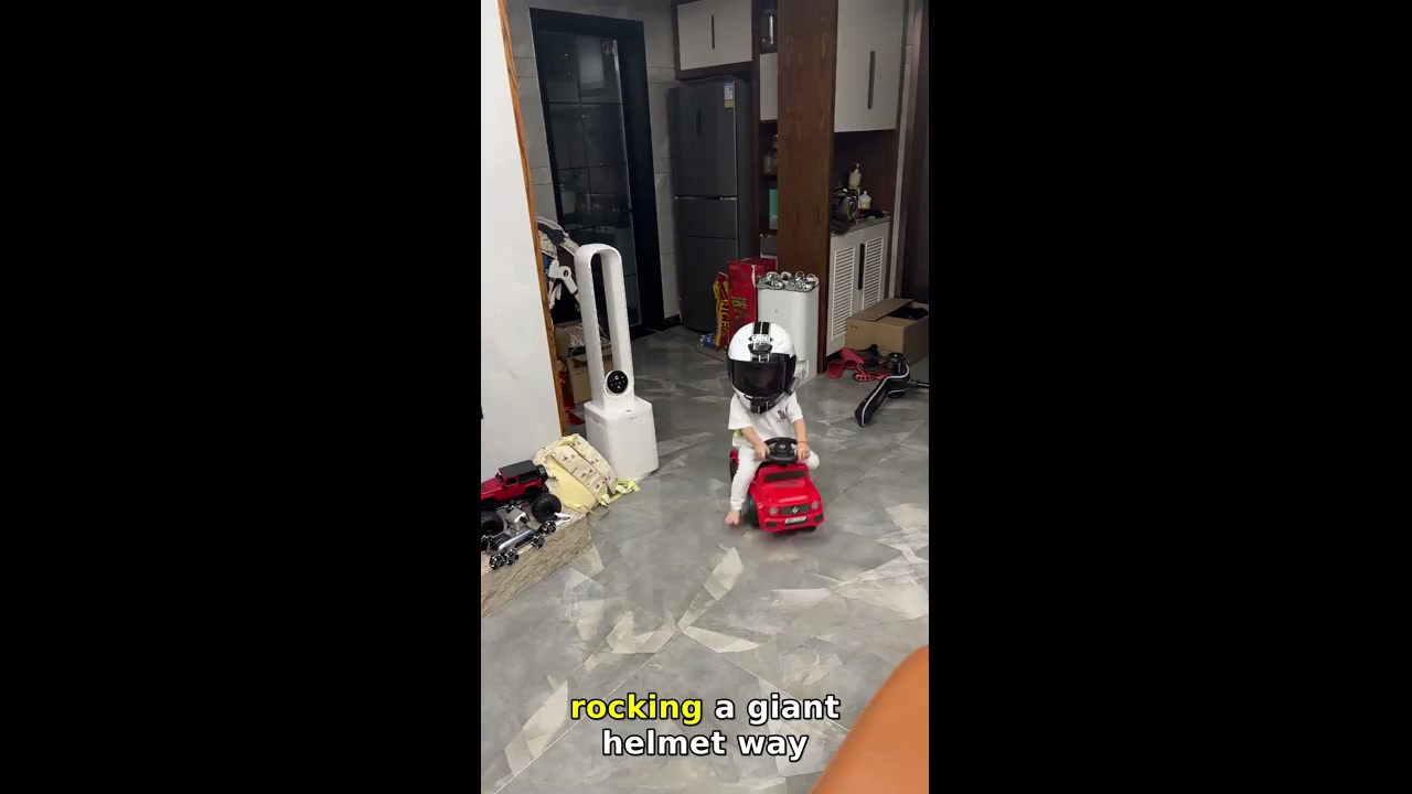 Toddler wears giant helmet while racing toy car