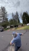 Man pulls tree with rope and it falls onto edge of house