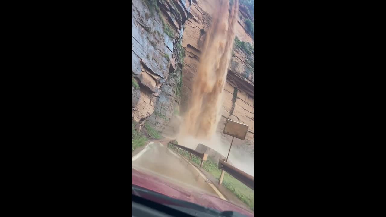 Driver passes through cascading floodwater on mountain road in Sichuan ...