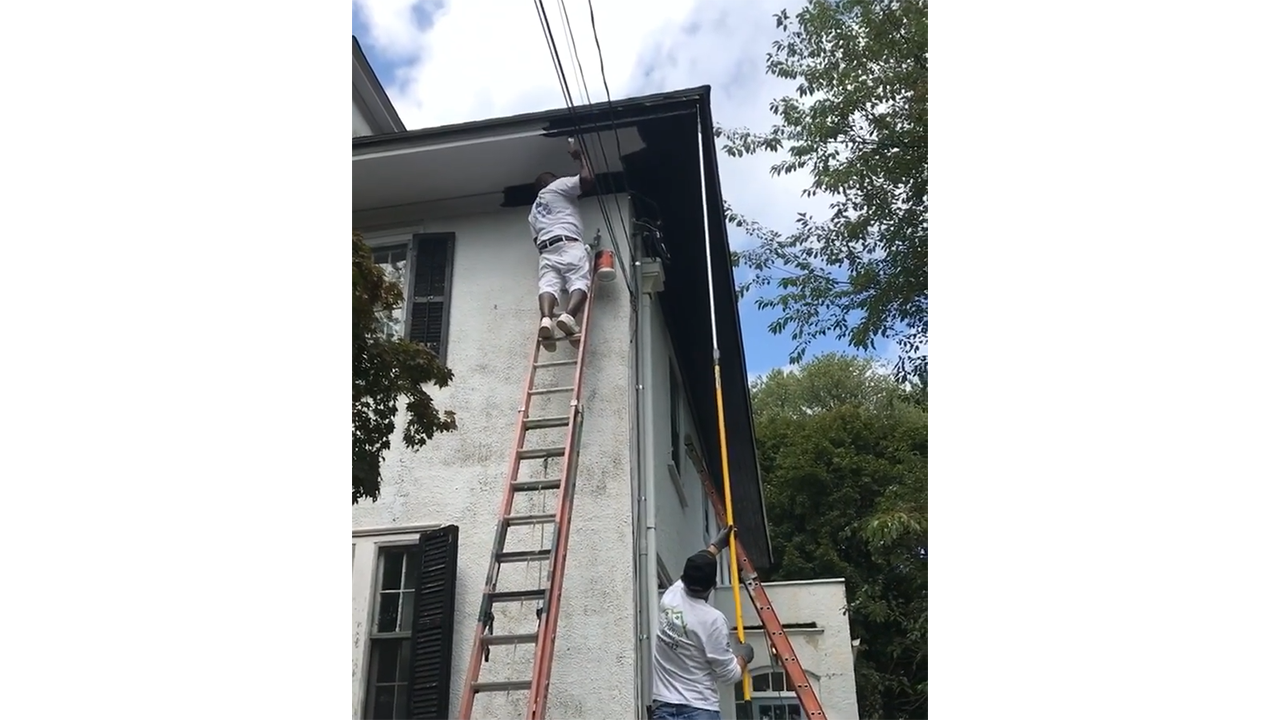 Painting high exterior fascia board with deep black coating creating ...