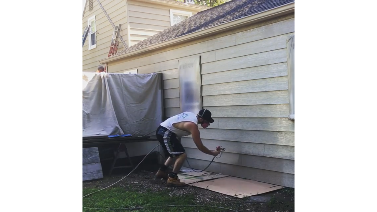 Spray painting exterior house siding with soft gray coating creating ...