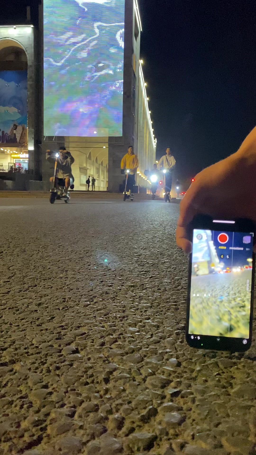 Nighttime scooter ride through a colorful cityscape