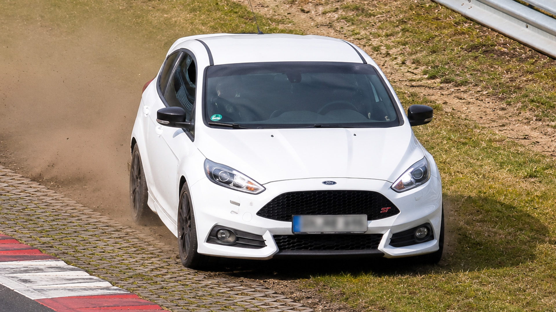 Staub wirbelt auf, während Fahrer die Kurvenlimits der Nordschleife ...