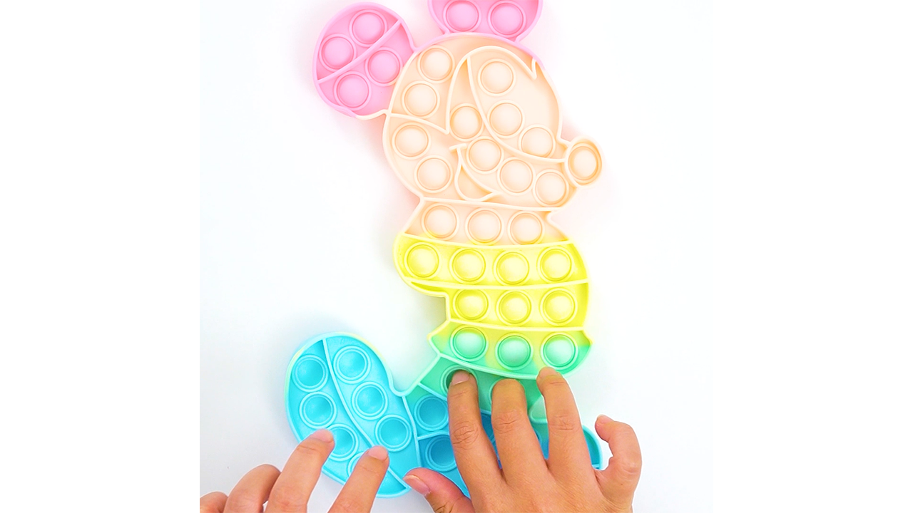 Playing with a colorful Minnie shaped pop it in soft rainbow colors